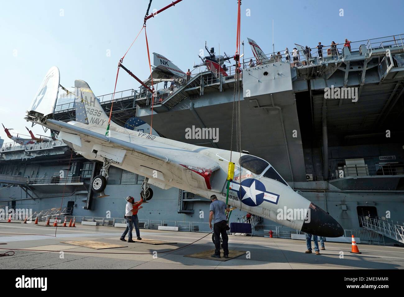 A crane lifts a historic Douglas F4D Skyray aircraft to a pier at the ...