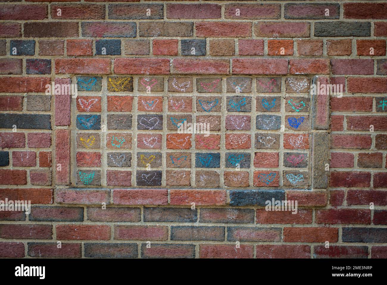 Hearts in different colors drawn on individual brick pieces in a urban ...