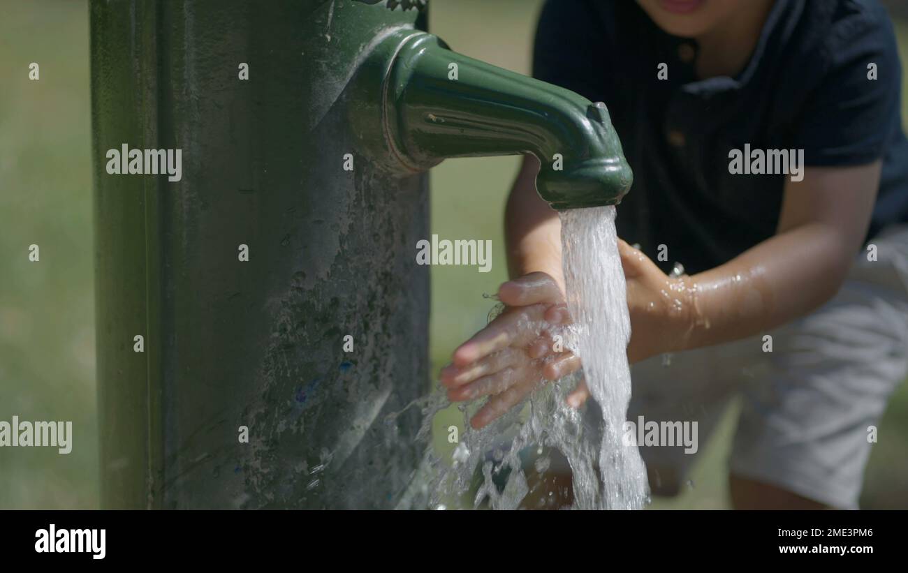 Small boy washing hands outside using public faucet water Stock Photo ...