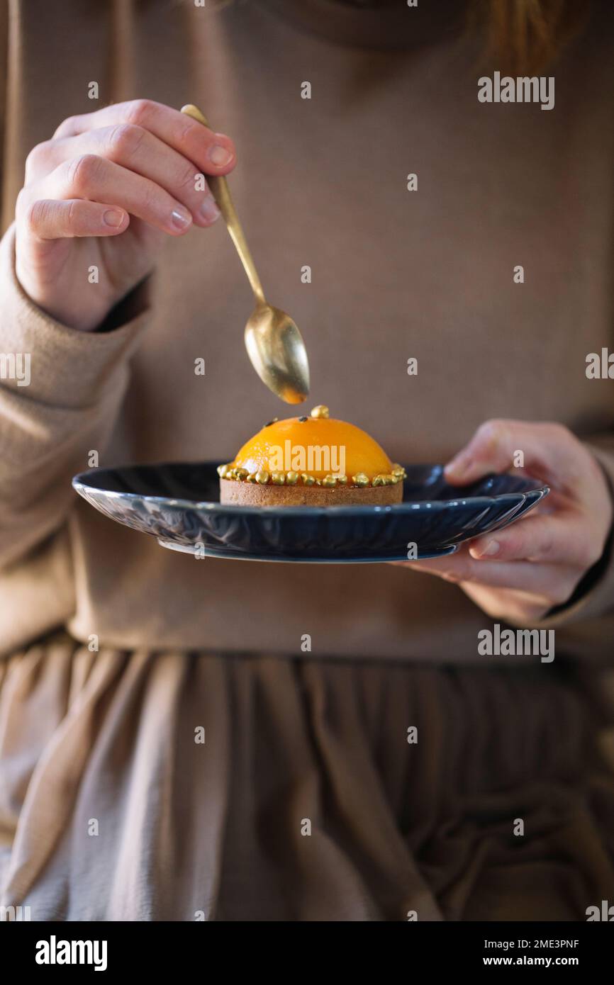 Woman eating peach tartlet with fork Stock Photo - Alamy