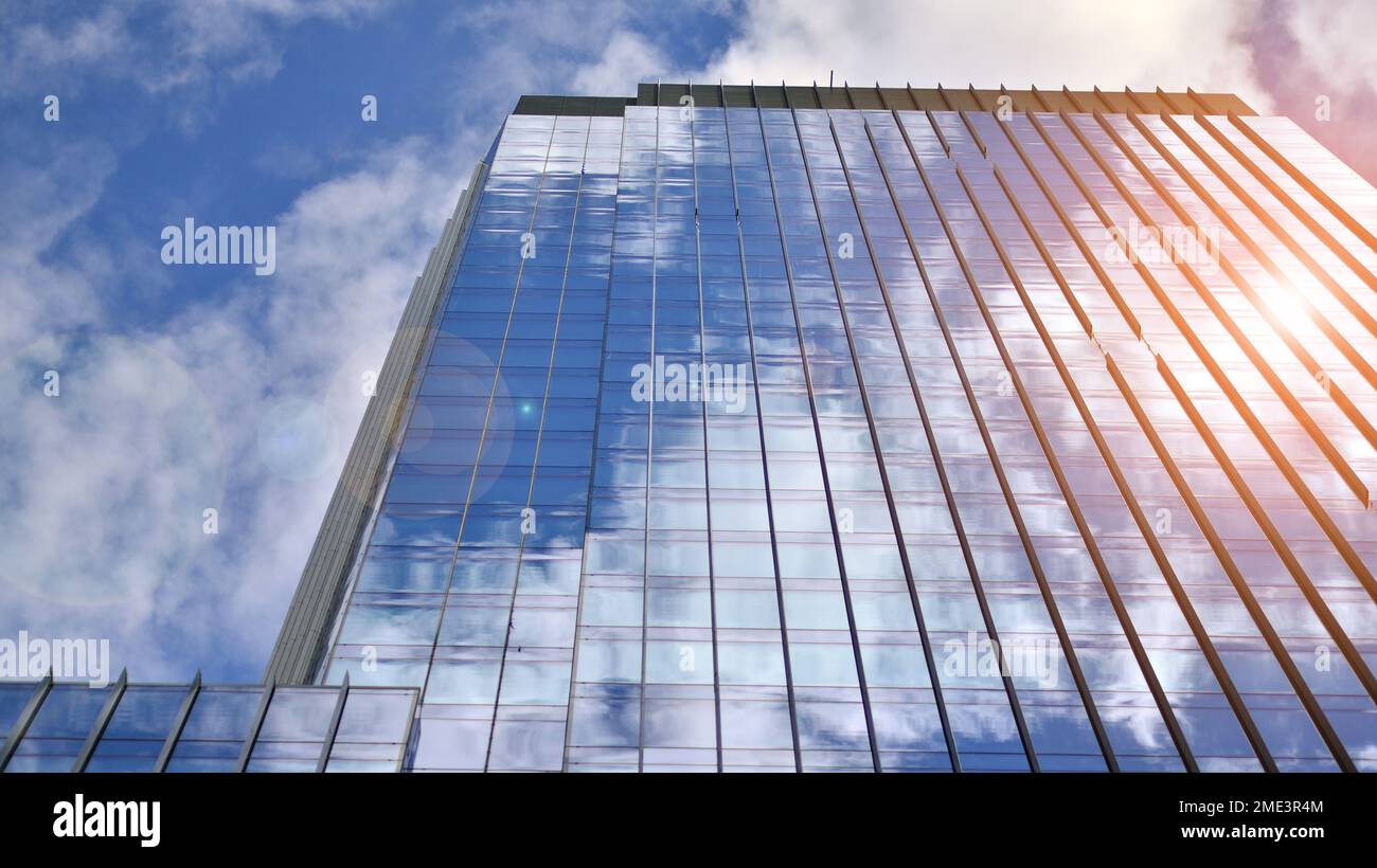 Modern glass facade against blue sky. Bottom view of a building in the ...