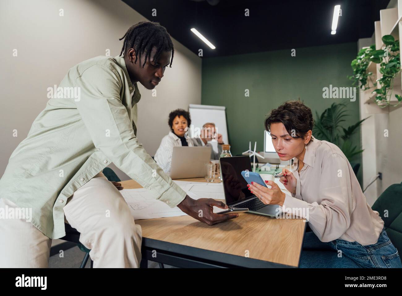 Business colleagues discussing over smart phones in office Stock Photo ...