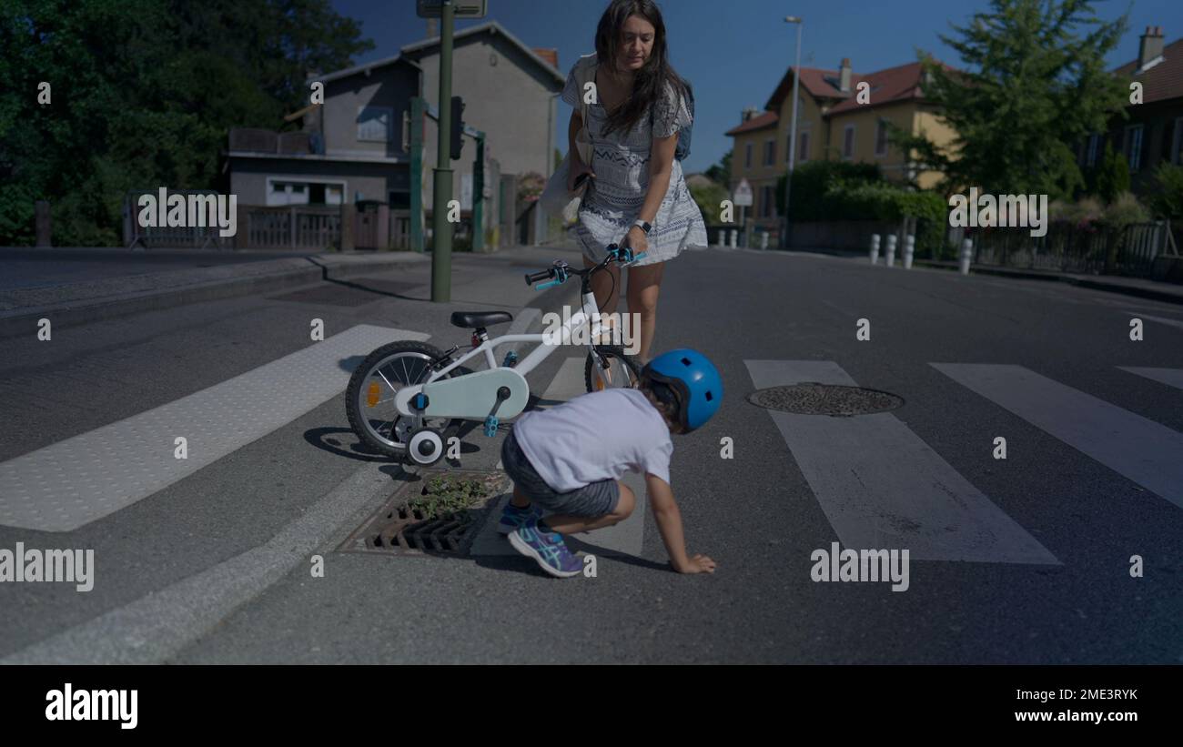Child falling to the ground while crossing street with bicycle mother ...