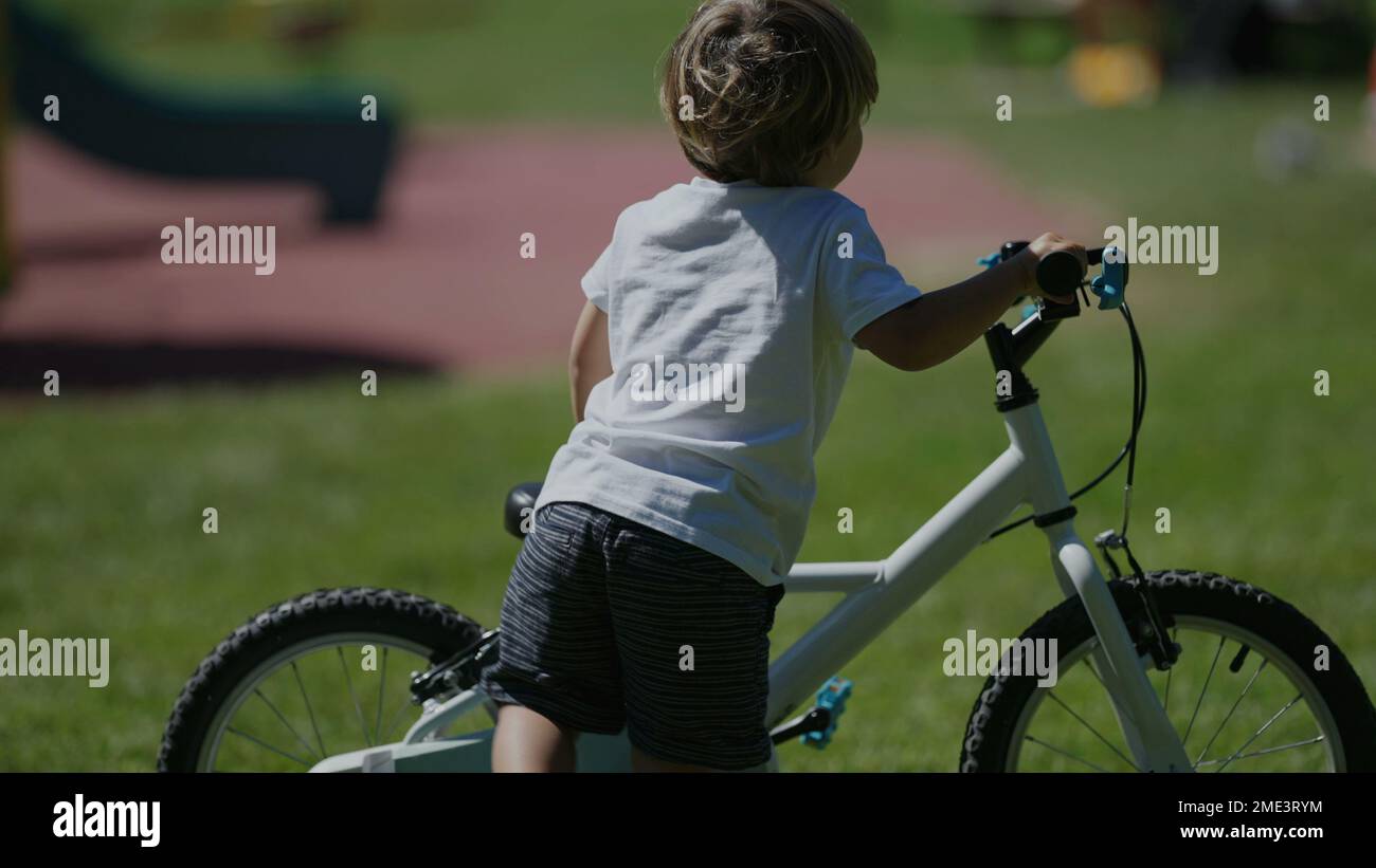 Child climbing on bicycle riding bike outside at park Stock Photo - Alamy