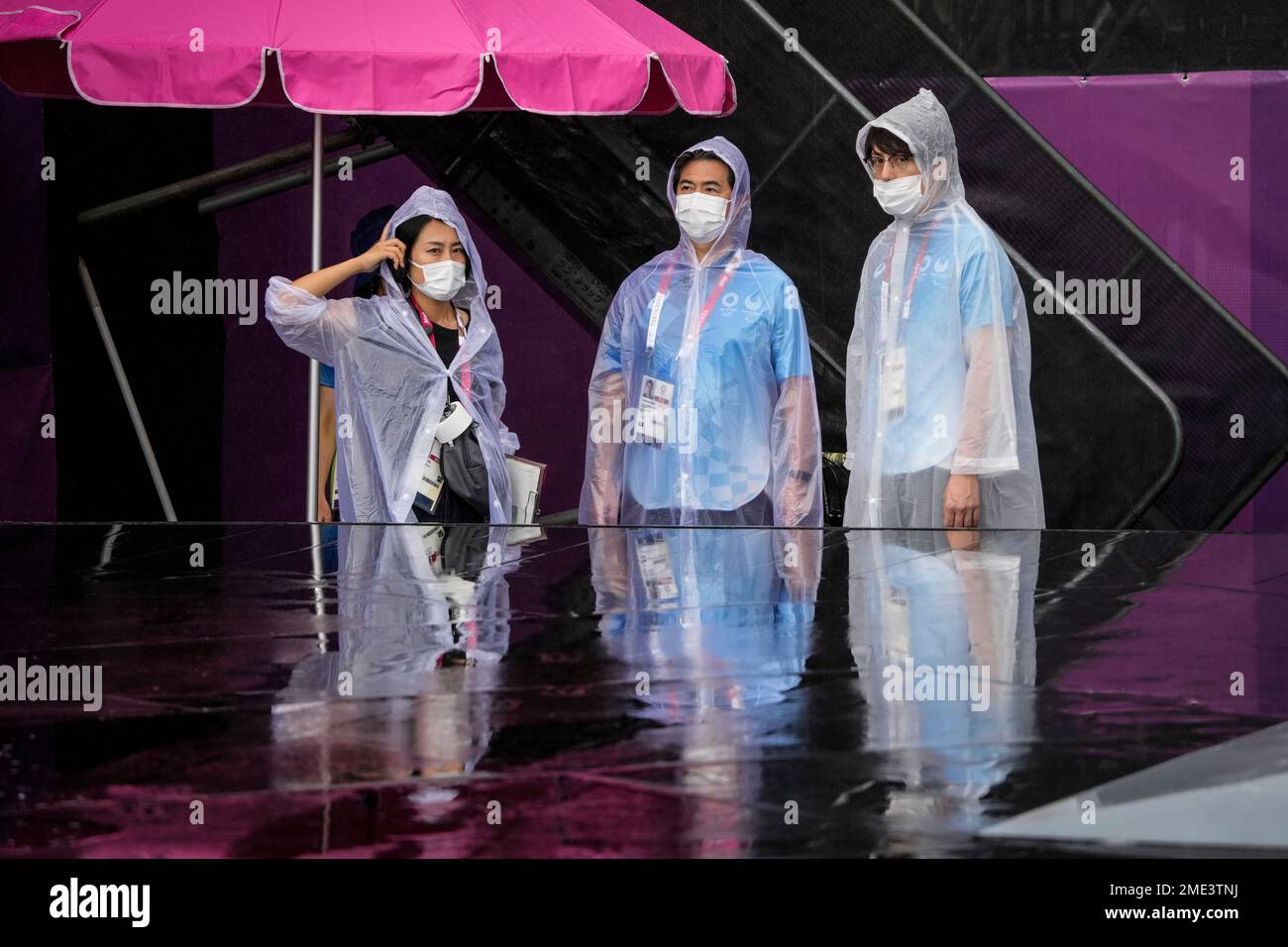 Members of medal ceremony staff stand in the rain ahead of a rehearsal ...