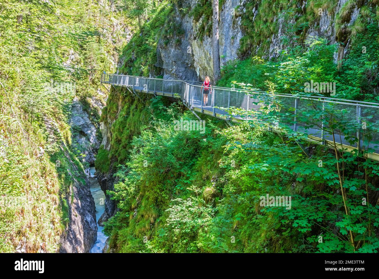 Austria, Female hiker walking along bridge stretching over Leutasch ...