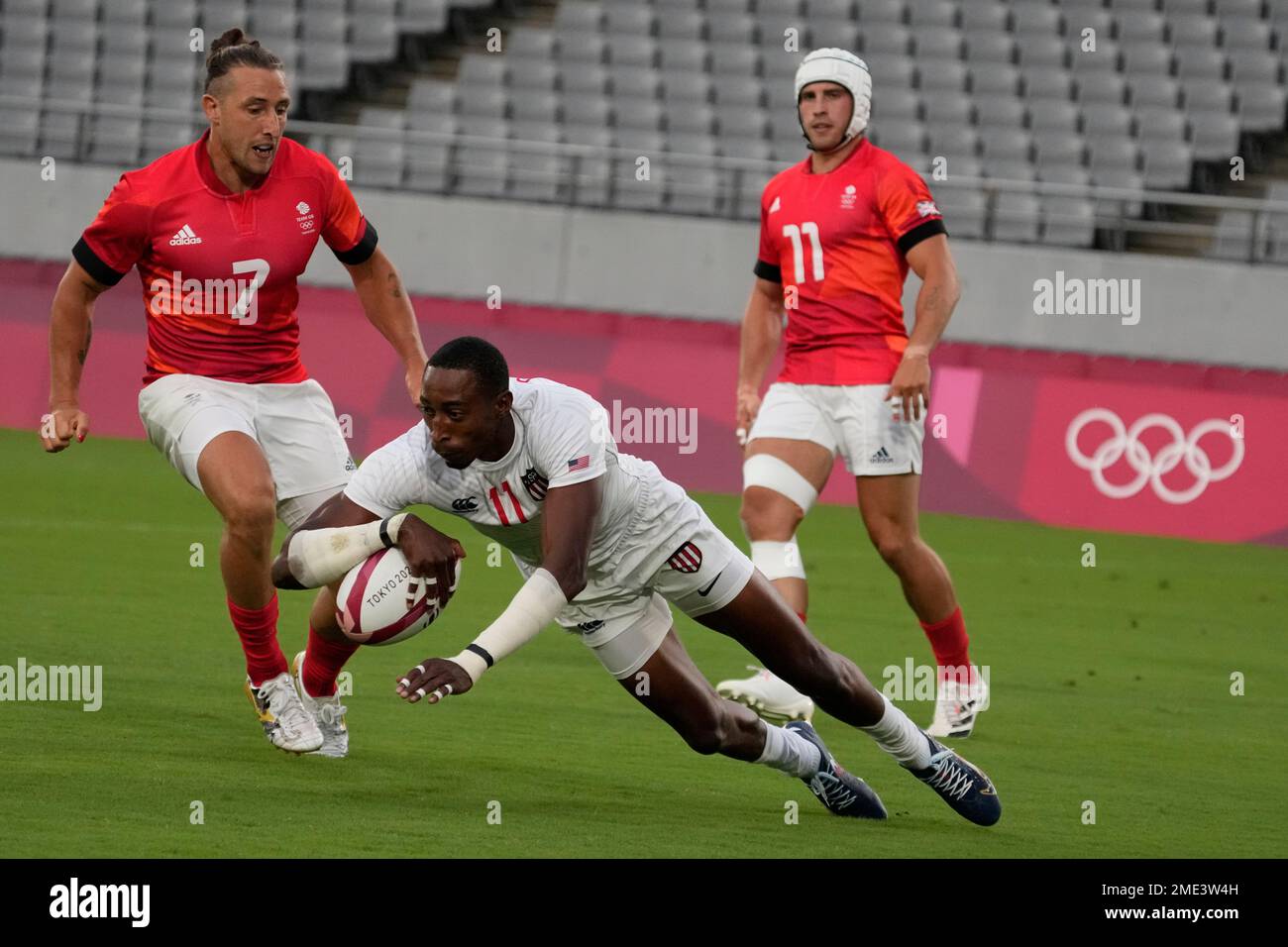 Perry Baker of the United States scores a try as Britain's Dan Bibby ...