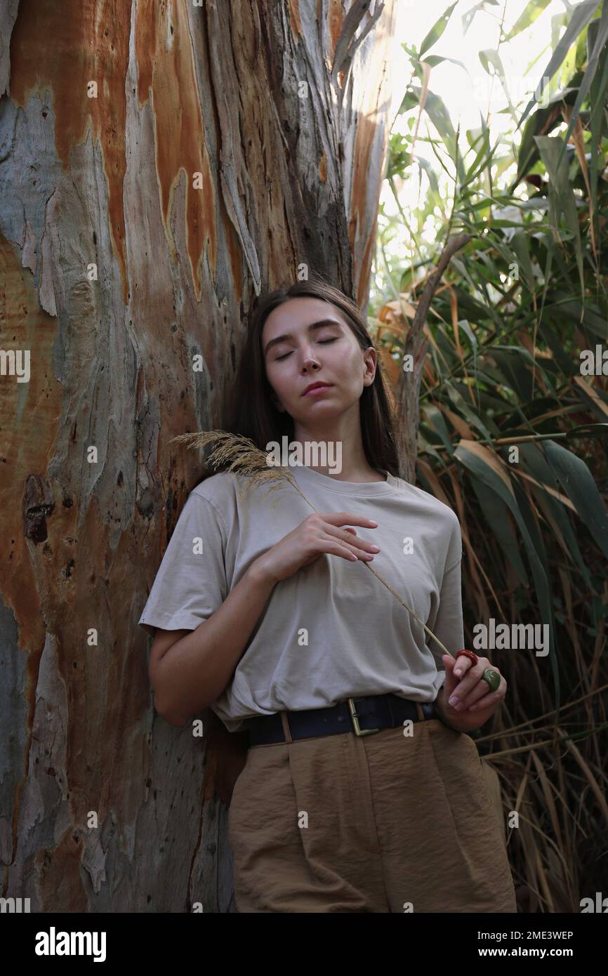 Young woman leaning on tree trunk hi-res stock photography and images ...