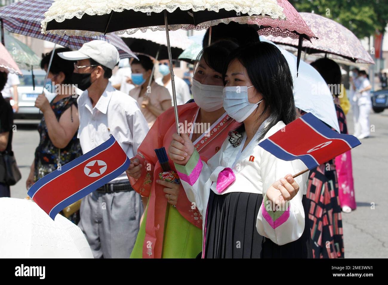 Pyongyang citizens holding North Korean flags watch a performance by an ...