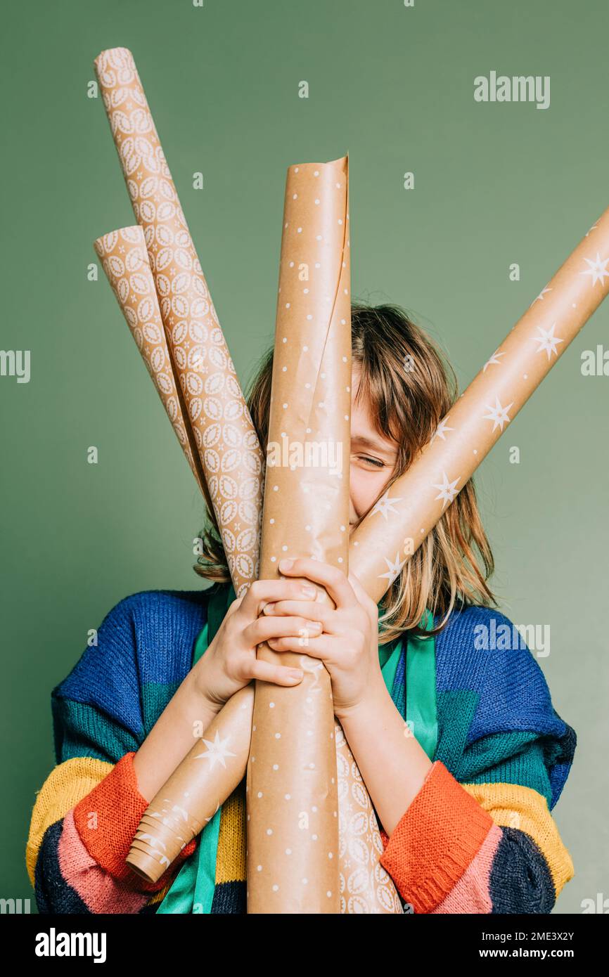 Girl with wrapping paper rolls standing in front of green wall Stock ...