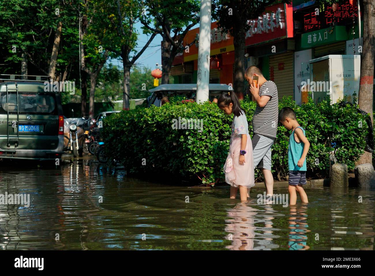 People walk along a flooded street in Xinxiang in central China's Henan ...