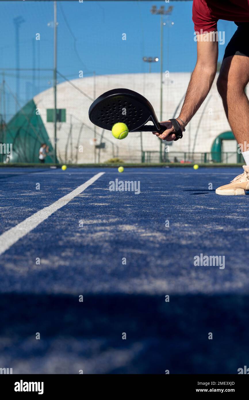 Hand of young man with racket playing paddle tennis at sports court ...