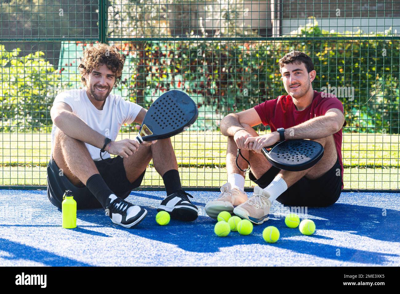 Friends sitting with tennis rackets and balls at sports court Stock ...