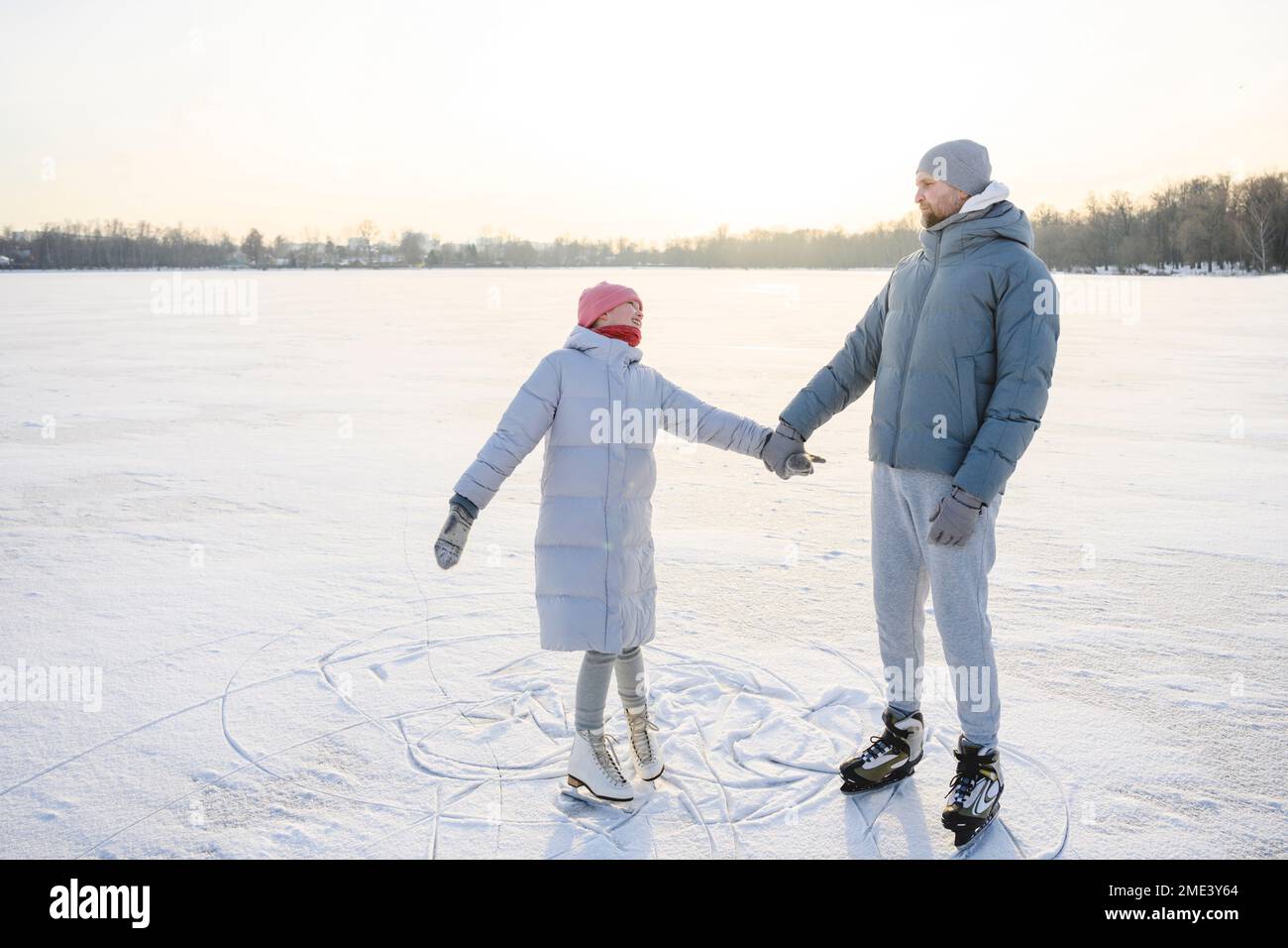 Father holding hands of daughter and practicing ice skating on winter ...