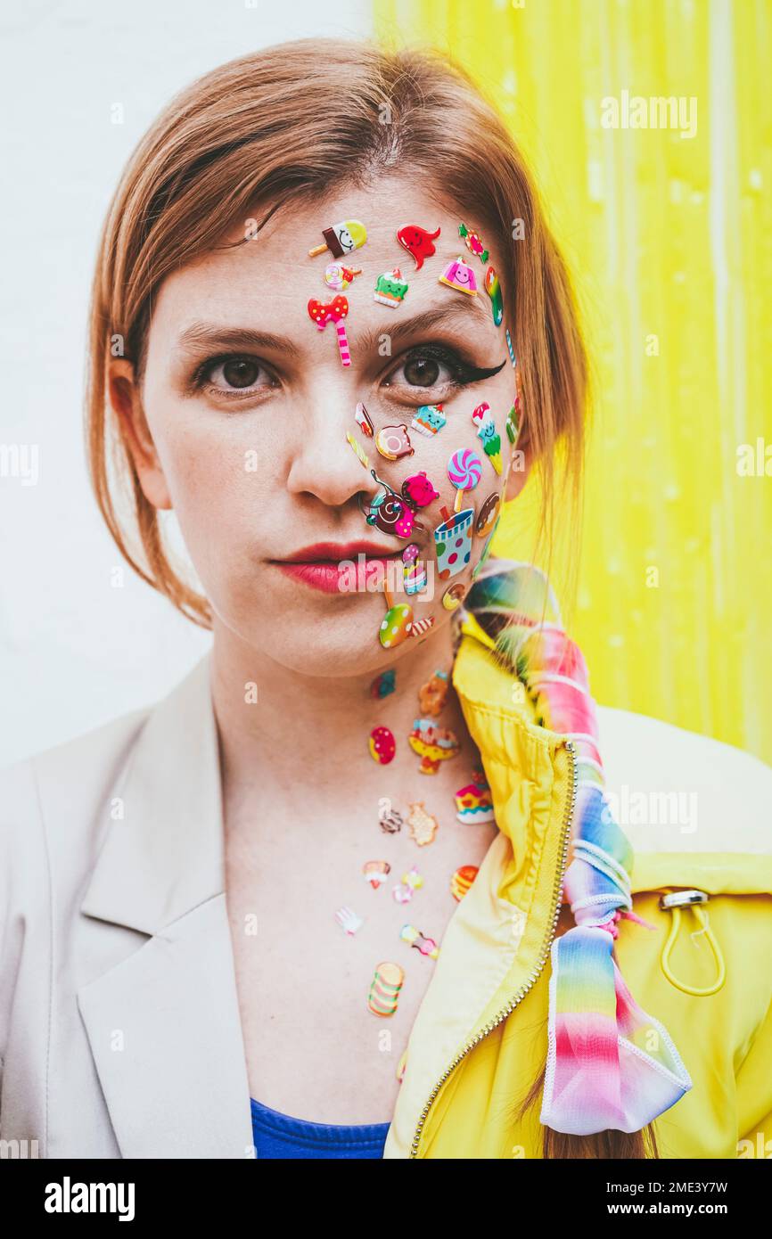 Woman with stickers on face in front of two tone wall Stock Photo - Alamy