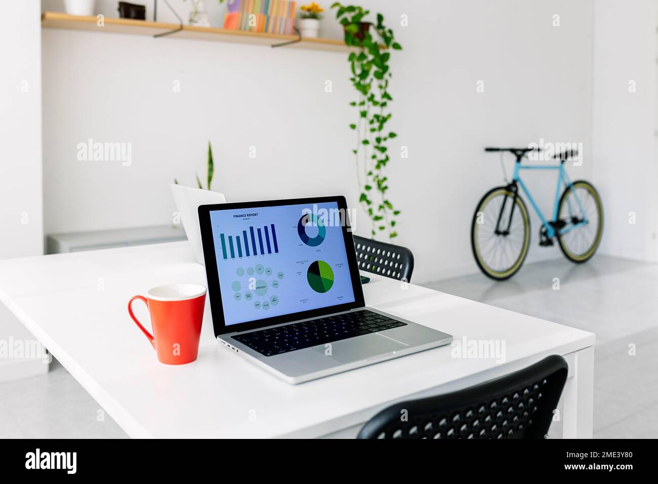 Bar graph and pie chart on laptop screen by coffee cup at desk in ...