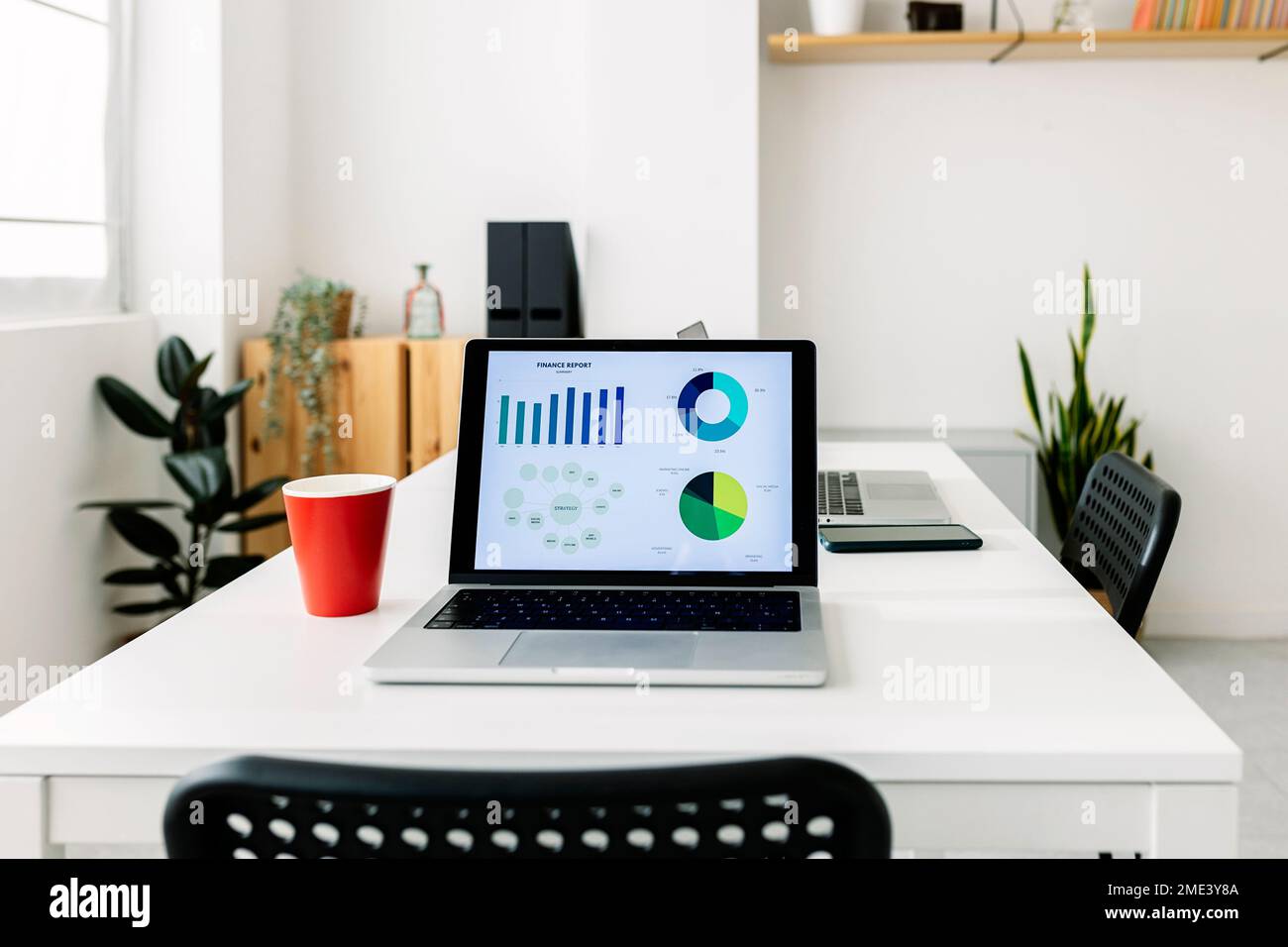 Bar graph and pie chart on laptop screen by coffee cup at office Stock ...