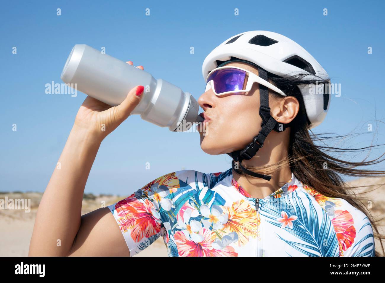 Thirsty cyclist drinking water under sky Stock Photo - Alamy
