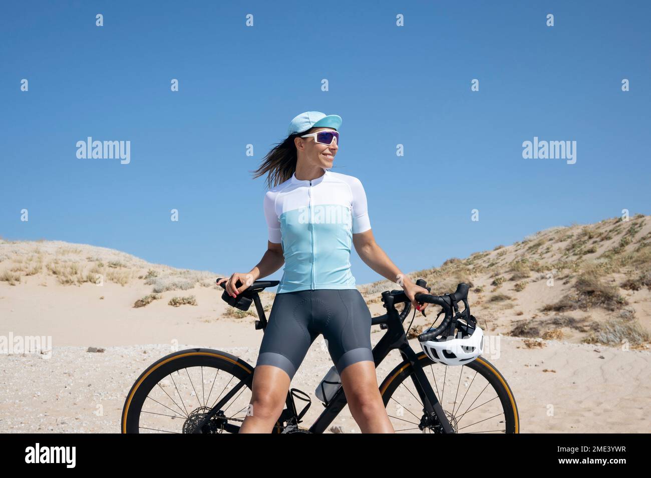 Happy cyclist standing with bicycle in front of sand dunes Stock Photo ...