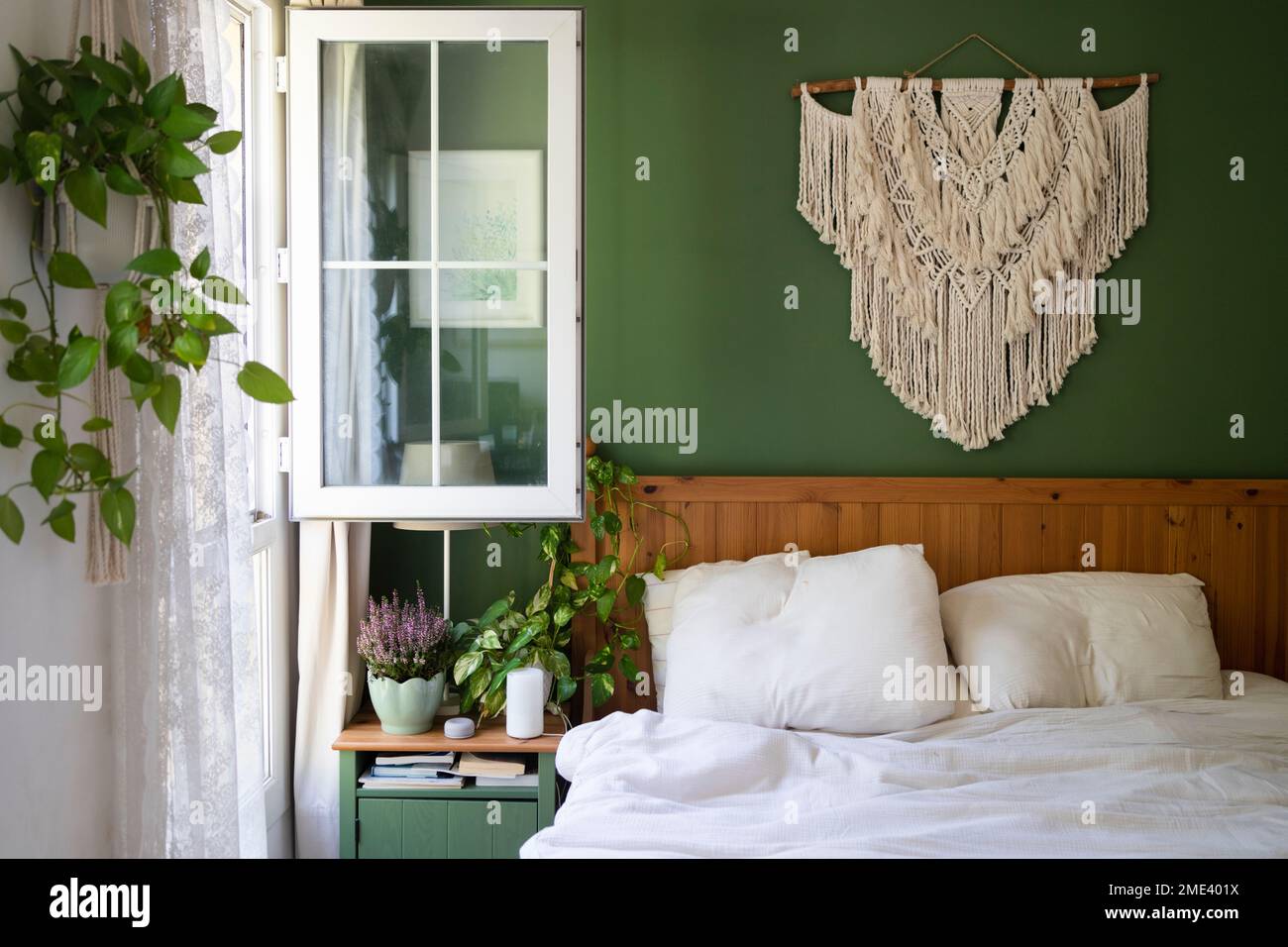 Macrame decoration hanging on green wall above bed in bedroom Stock ...