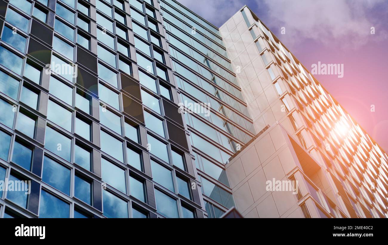 Modern glass facade against blue sky. Bottom view of a building in the ...