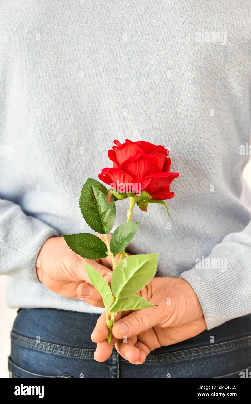 Photo of man holding a red rose behind his back Stock Photo - Alamy