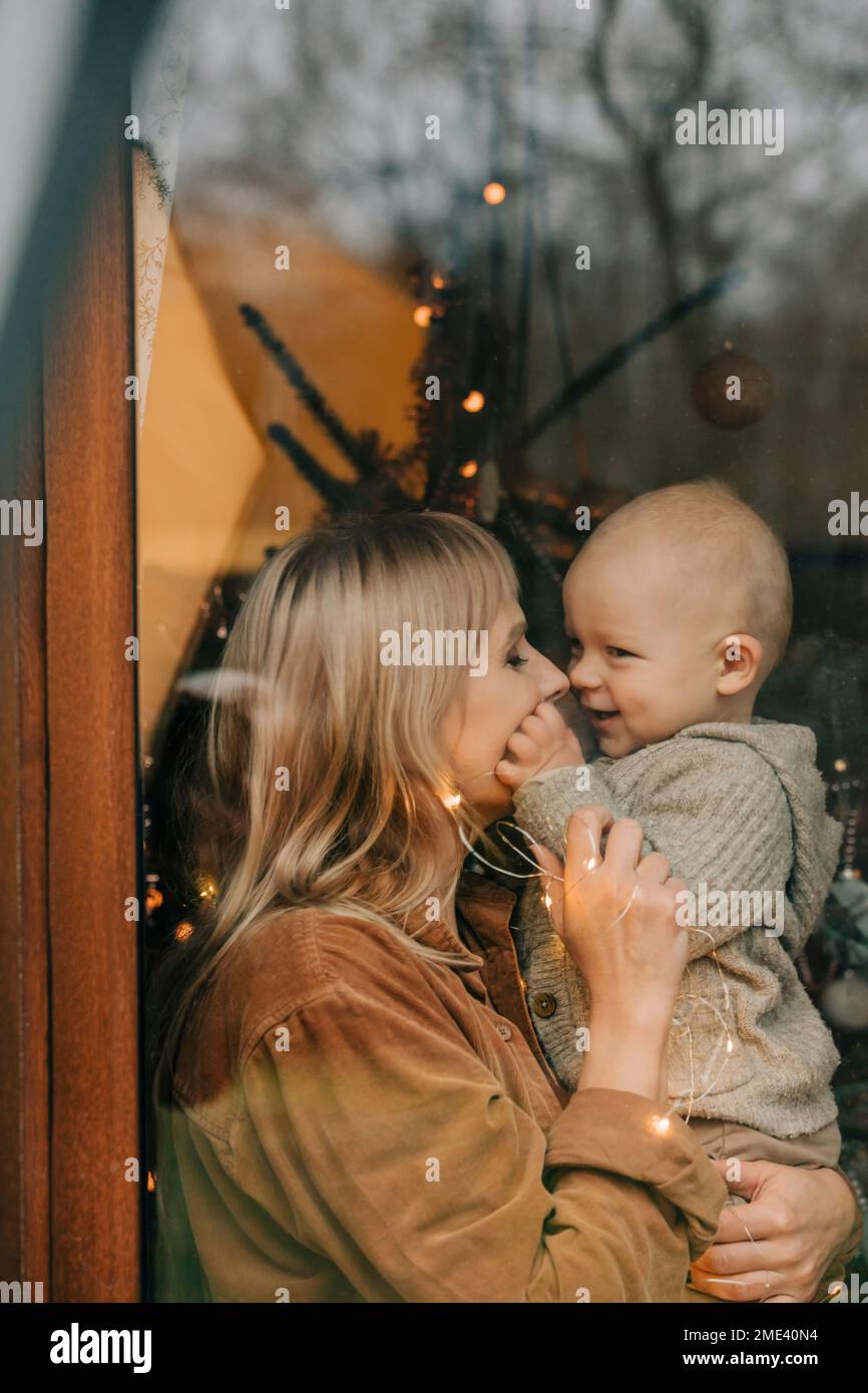 Mother with illuminated string light carrying smiling baby boy Stock ...