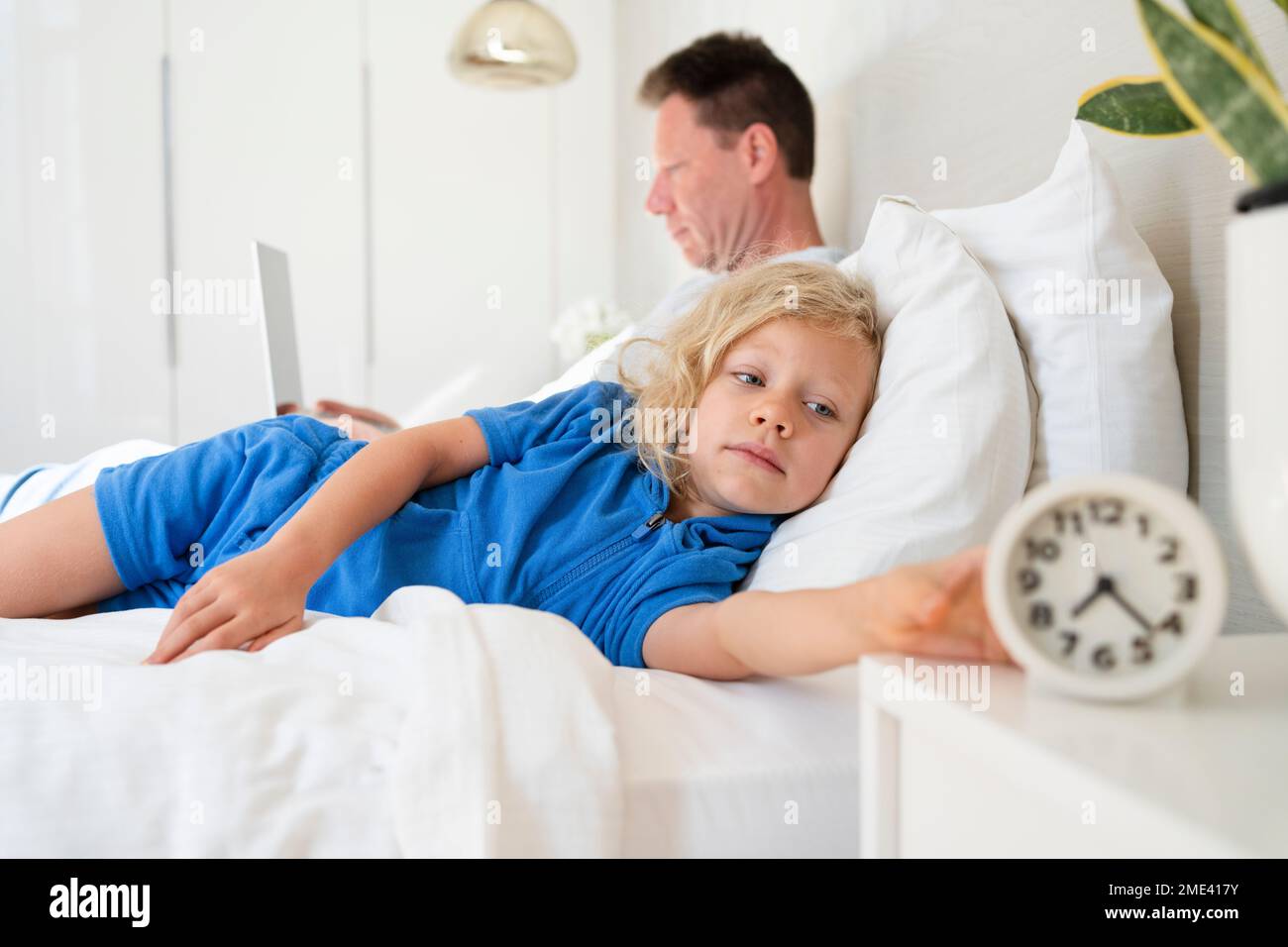 Girl holding alarm clock lying on bed by father in bedroom Stock Photo ...