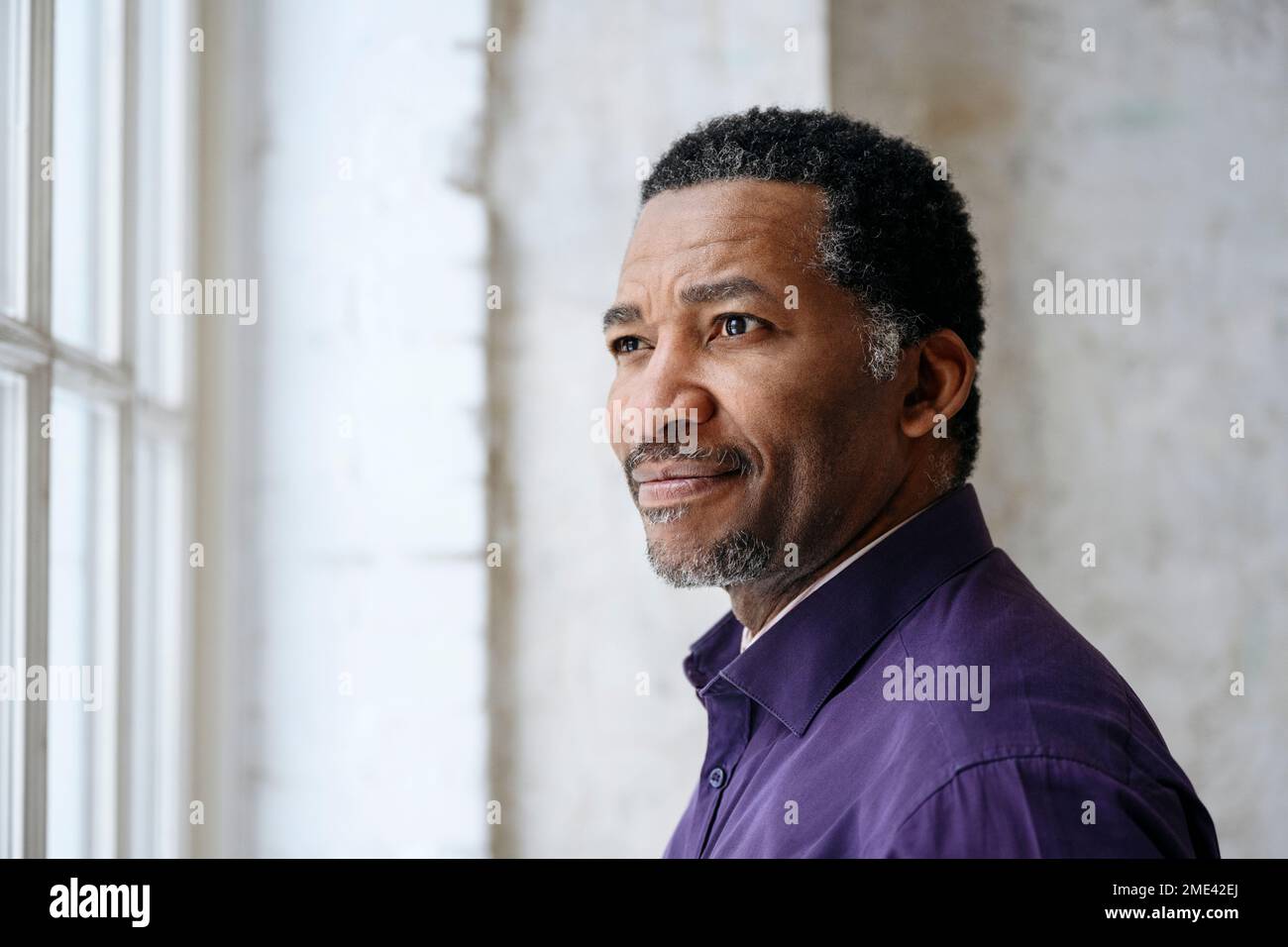 Thoughtful mature man looking out through window Stock Photo - Alamy