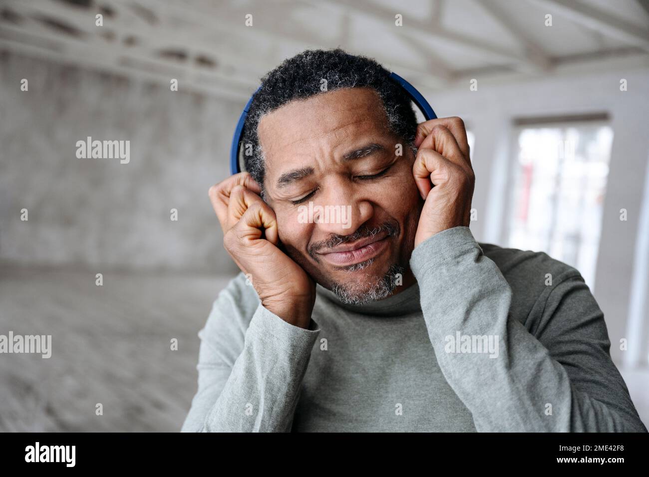 Man enjoying music listening through wireless headphones at home Stock ...
