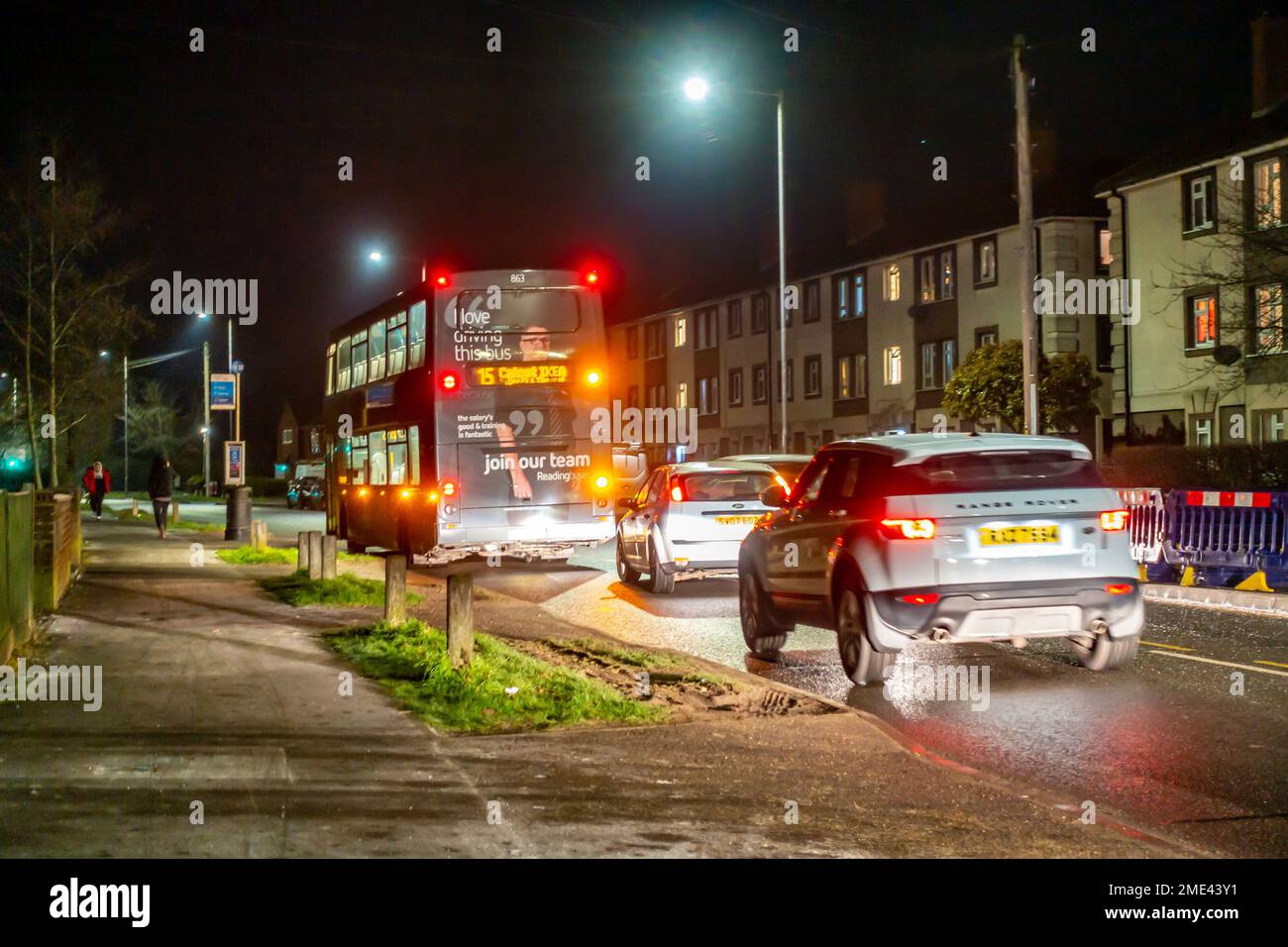 A couple of cars follow a double decker bus along a road at night ...