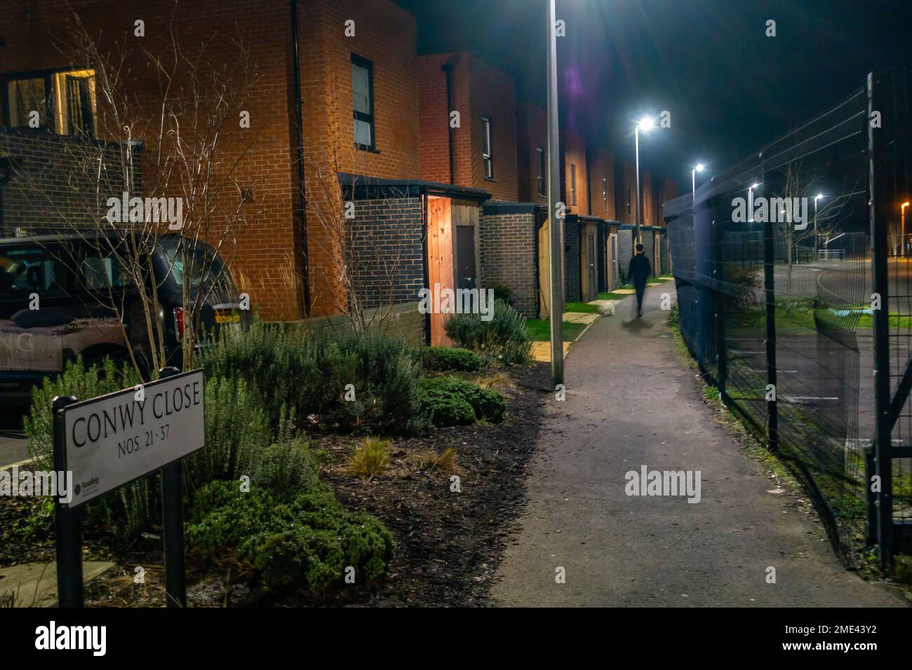 A footpath at night lit with street lights with the doorways to modern ...