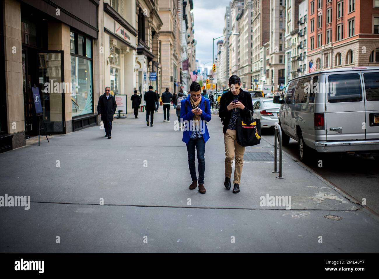 Two commuters walking to work while looking at their smartphone Stock ...