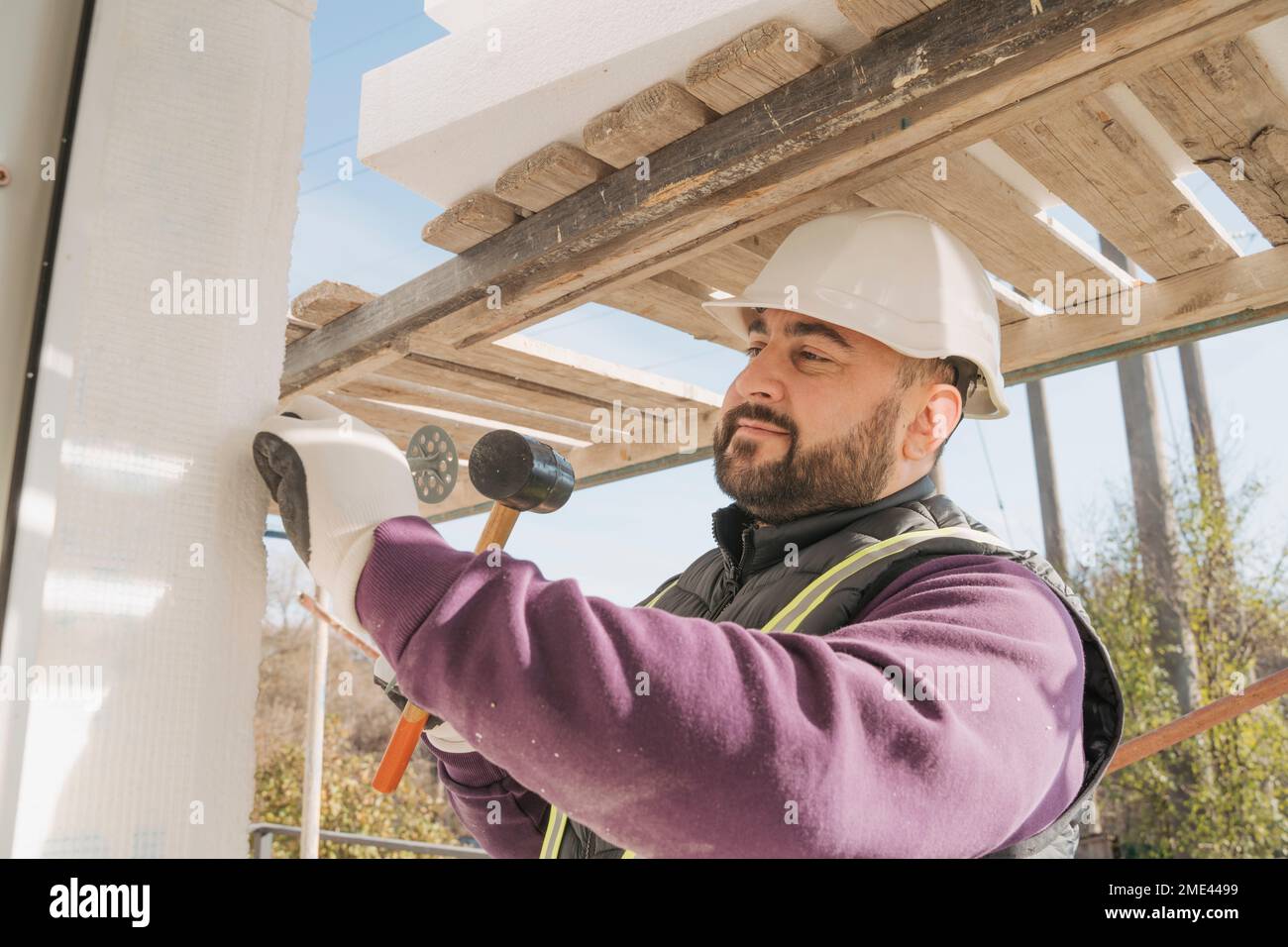 Construction worker using hammer on wall at site Stock Photo - Alamy