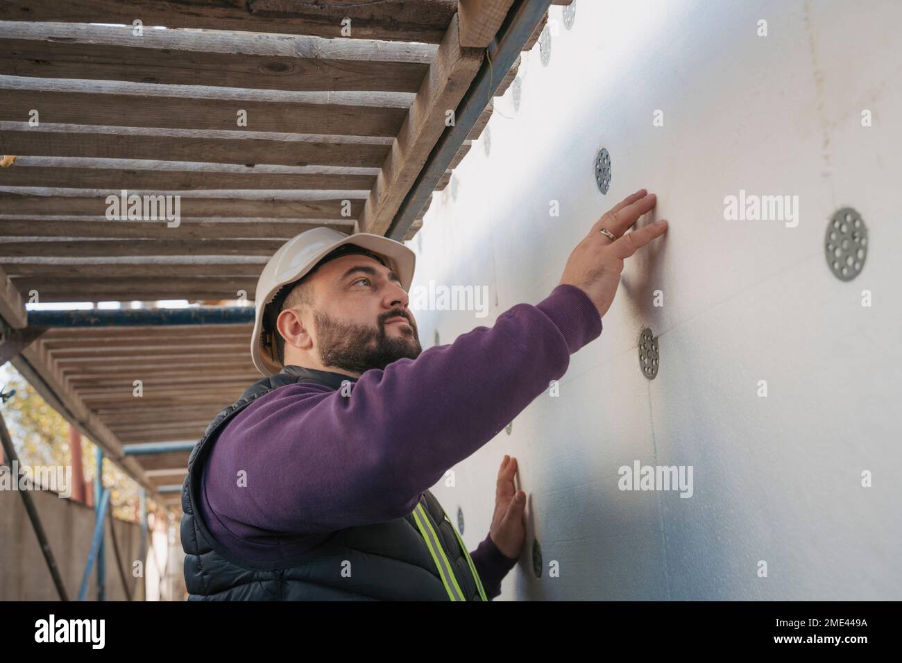 Construction worker examining polystyrene foam wall on site Stock Photo ...