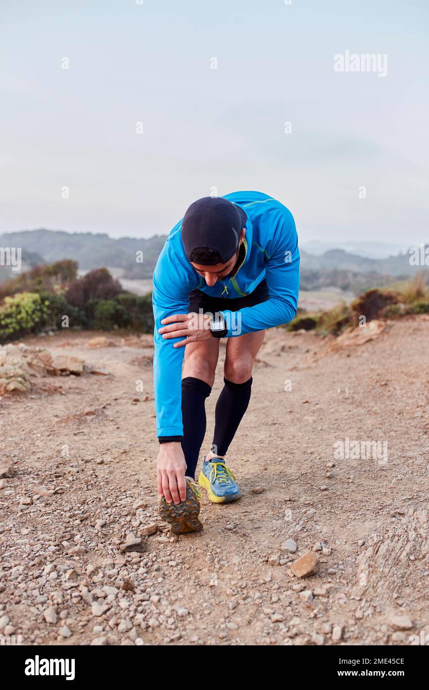Man stretching leg on dirt road Stock Photo - Alamy