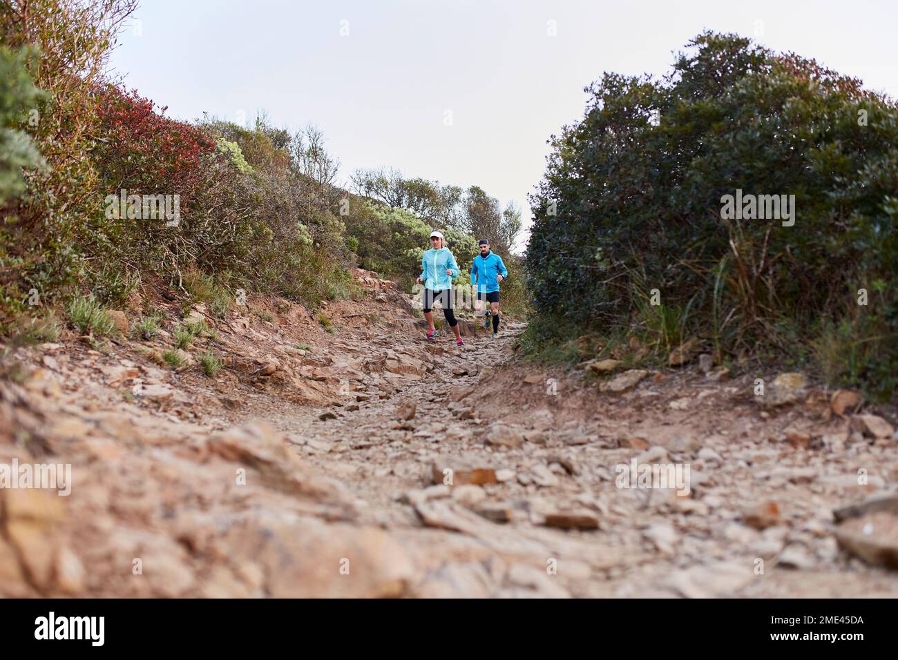 Couple running down on rocky path in morning Stock Photo - Alamy