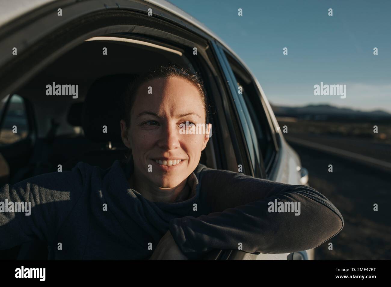 Thoughtful smiling woman sitting in car looking out of window Stock ...