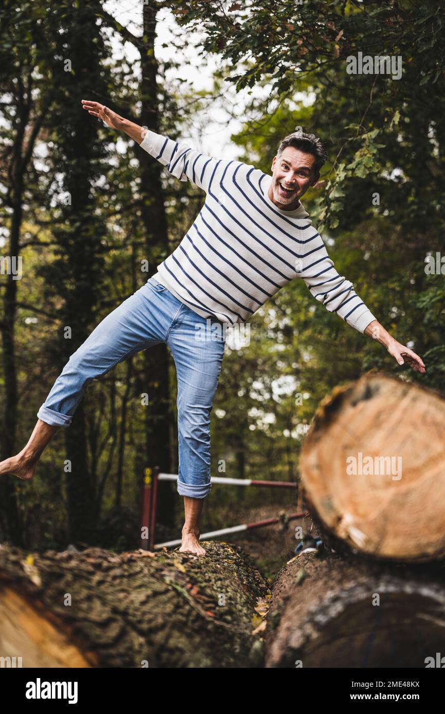 Happy mature man with arms outstretched balancing on log Stock Photo ...
