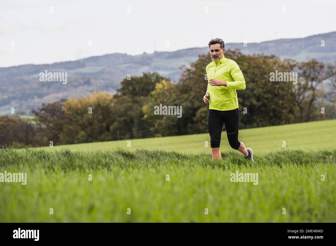 Mature man running on grass in meadow Stock Photo - Alamy