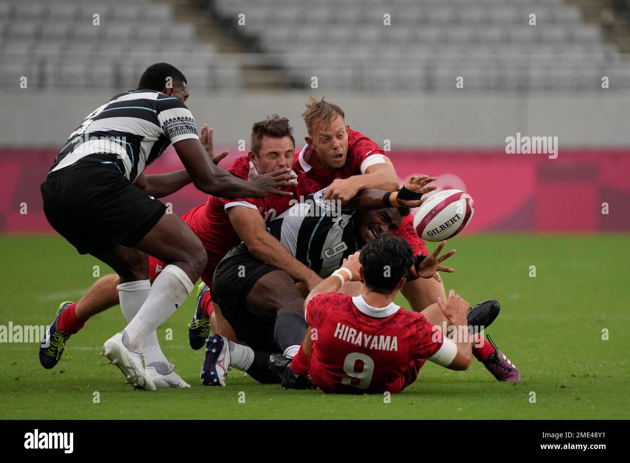 Fiji's Jerry Tuwai, center, is swarmed by Canada's Nathan Hirayama ...