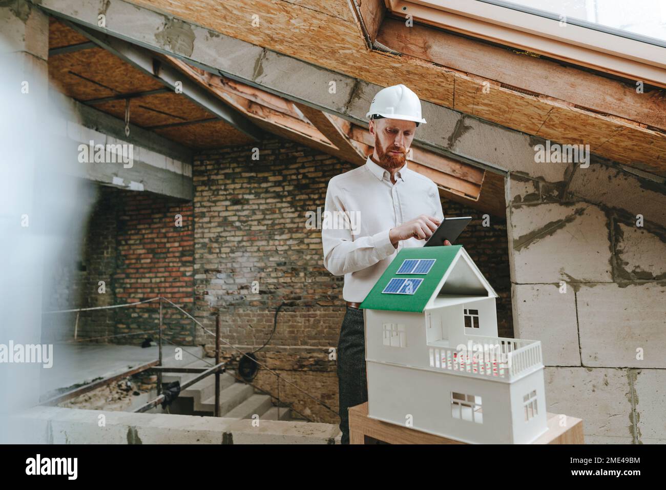 Architect analyzing house model using tablet PC at construction side ...