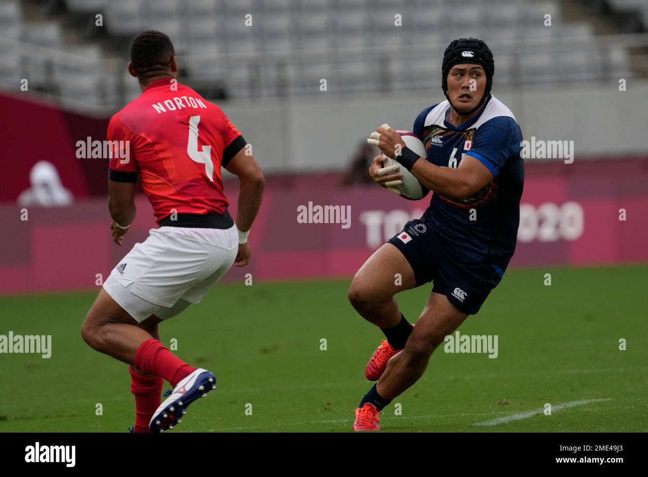 Japan's Masakatsu Hikosaka runs with the ball past Britain's Dan Norton ...