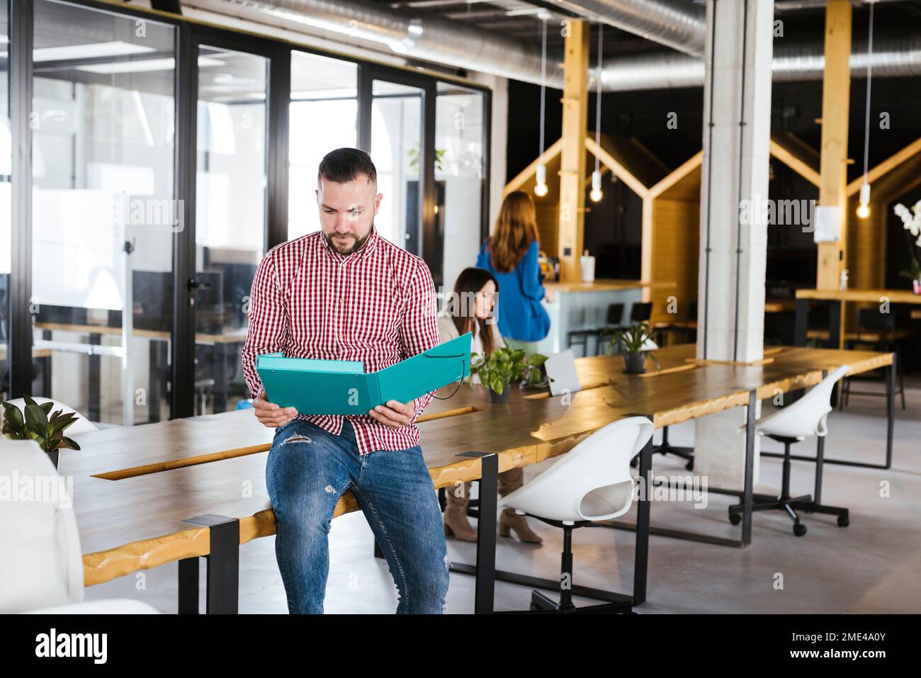 Businessman reading documents sitting on desk in office Stock Photo - Alamy