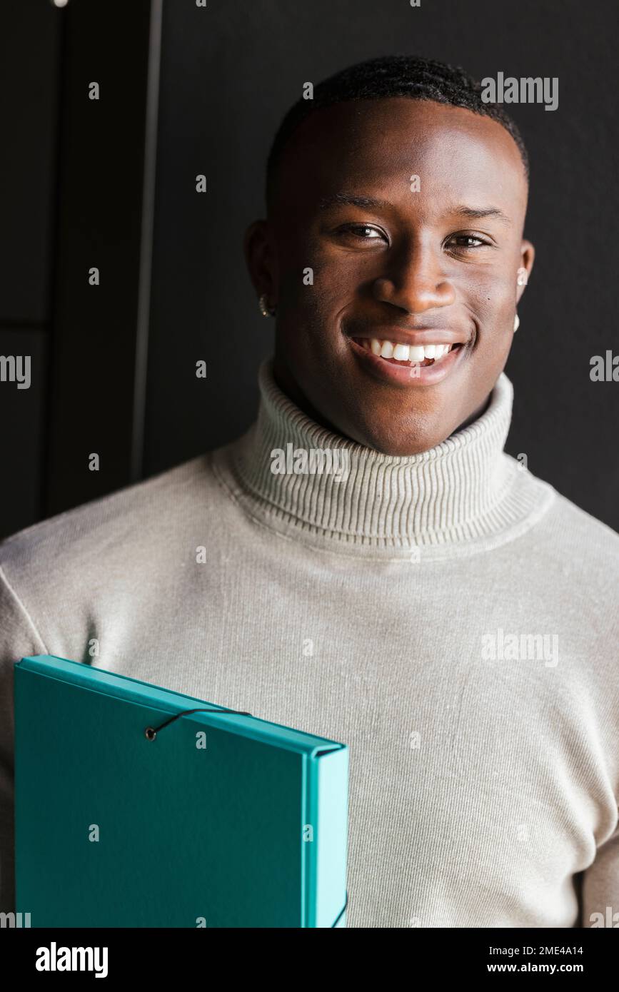Happy businessman with file folder in front of wall Stock Photo - Alamy