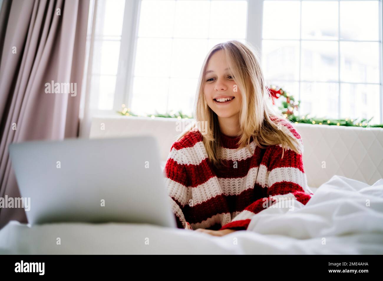 Happy girl using laptop in bedroom at home Stock Photo - Alamy