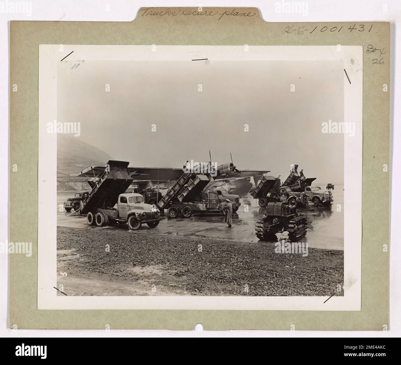 Trucks are positioned as a windbreak to protect a Coast Guard plane ...