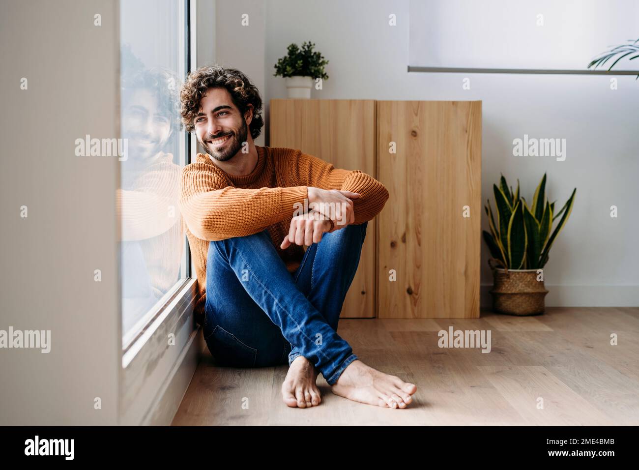 Happy young man looking through glass window Stock Photo - Alamy