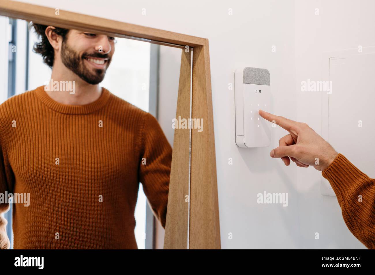 Happy young man setting alarm system at home Stock Photo - Alamy