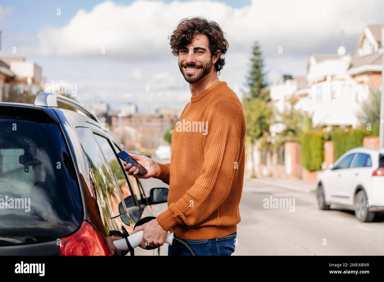 Happy man charging car at electric vehicle charging station Stock Photo ...